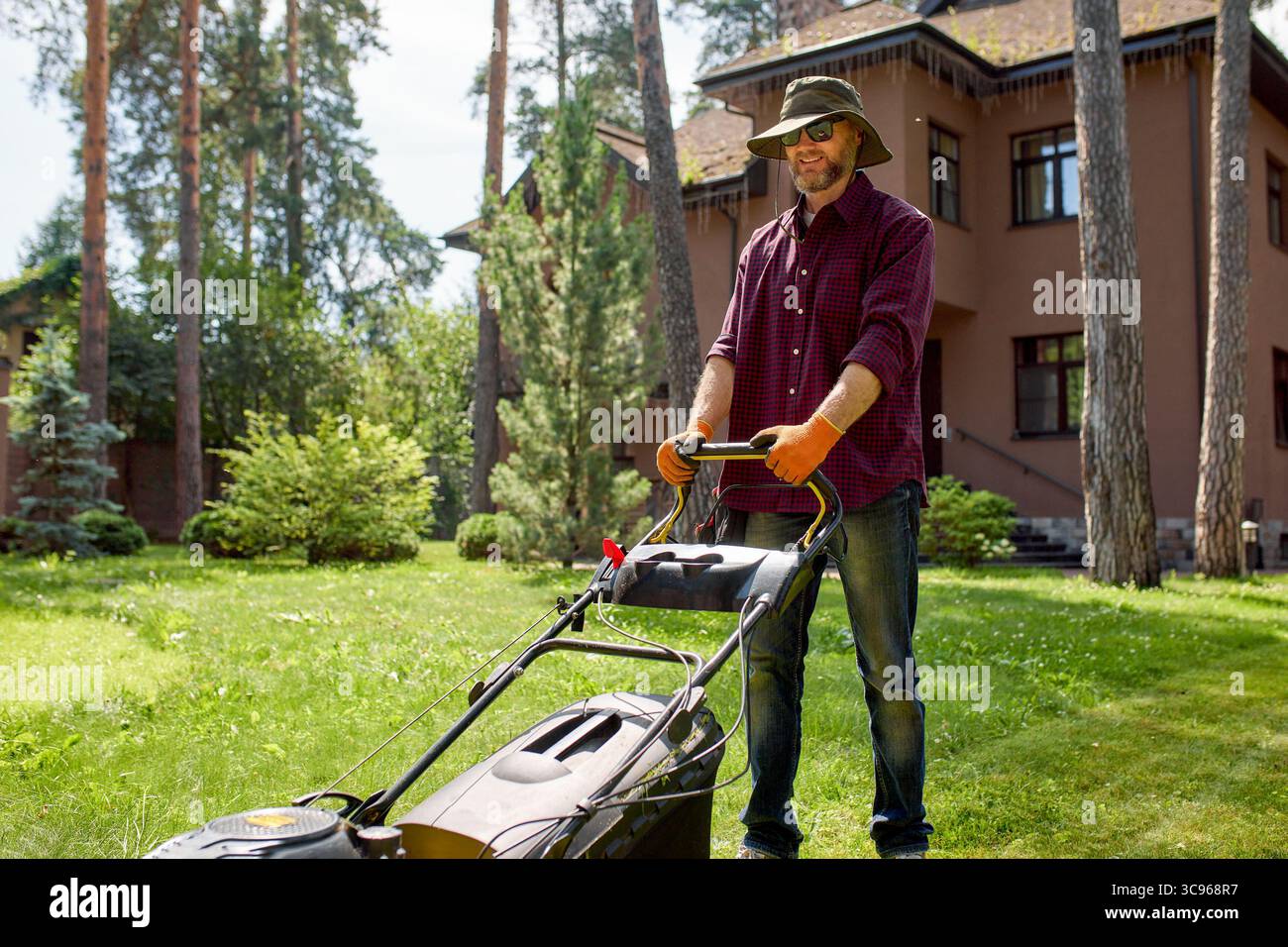 A man is enjoying outdoor work while mowing a lush green lawn in a ...