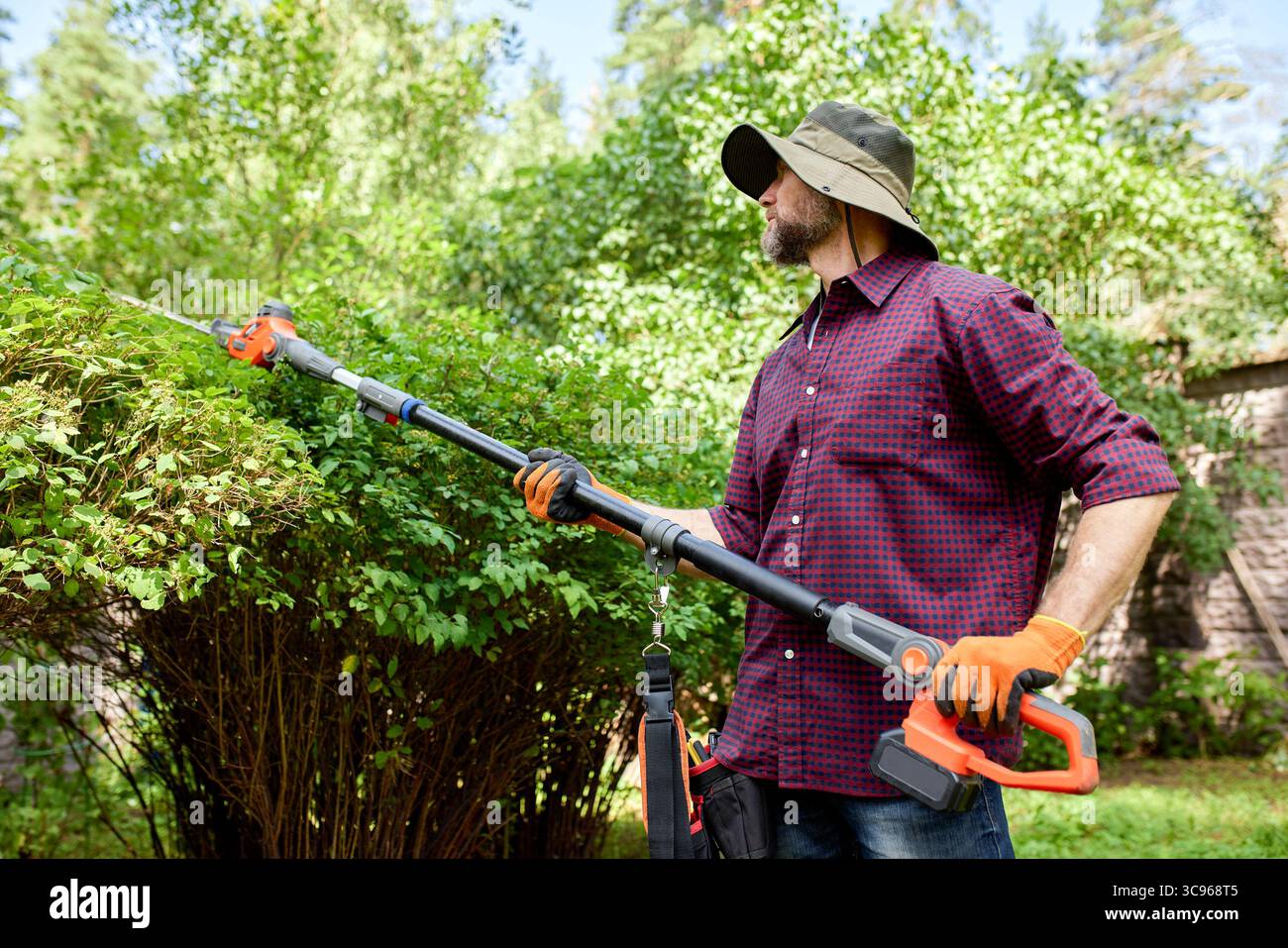 A gardener wearing protective clothing is maintaining the greenery of a ...
