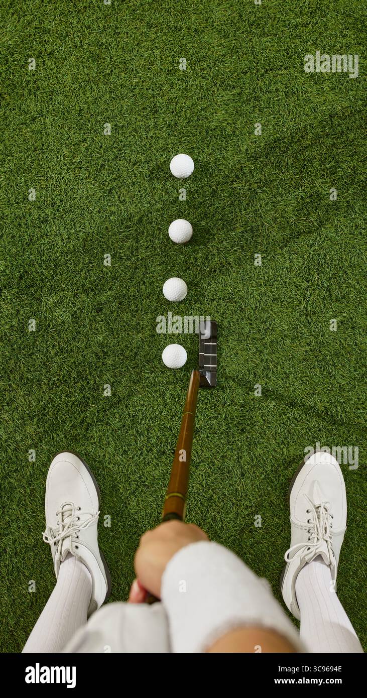 Top view of golfer feet and putter with three balls aligned on green ...