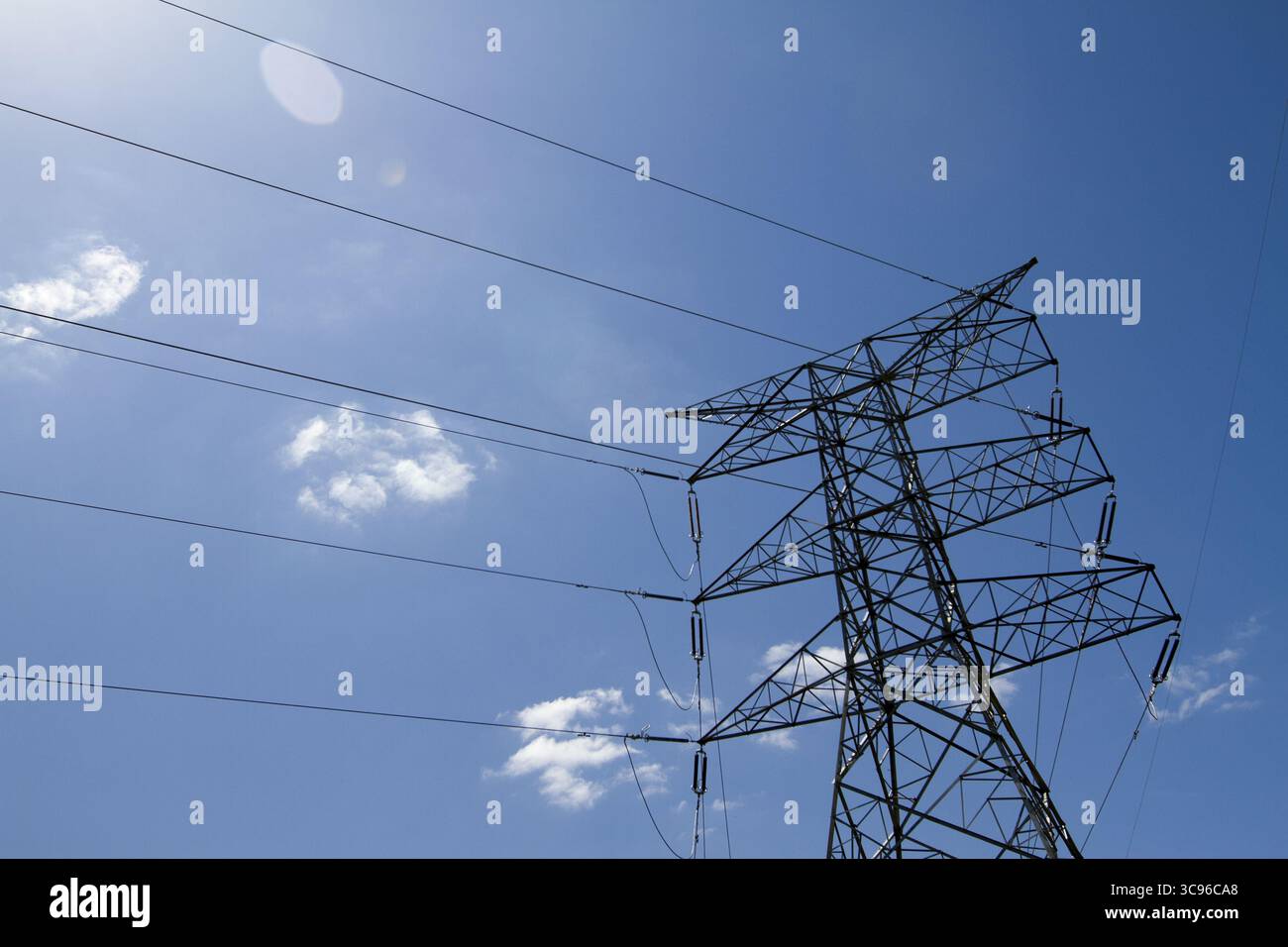 View of a towering electricity pylon silhouetted against a vibrant blue ...