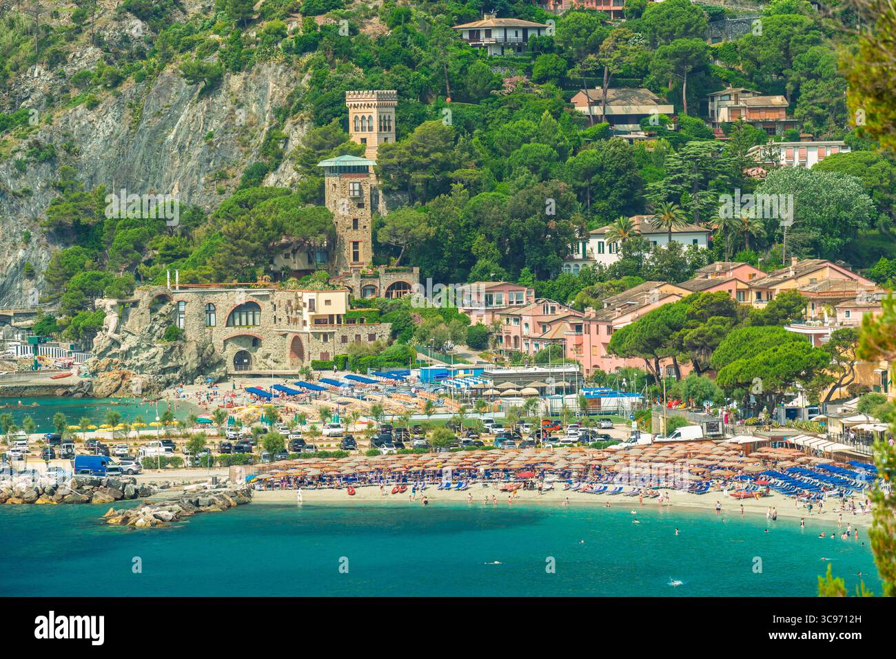 Beachgoers and sunbathers relax on the beach in the coastal village of ...