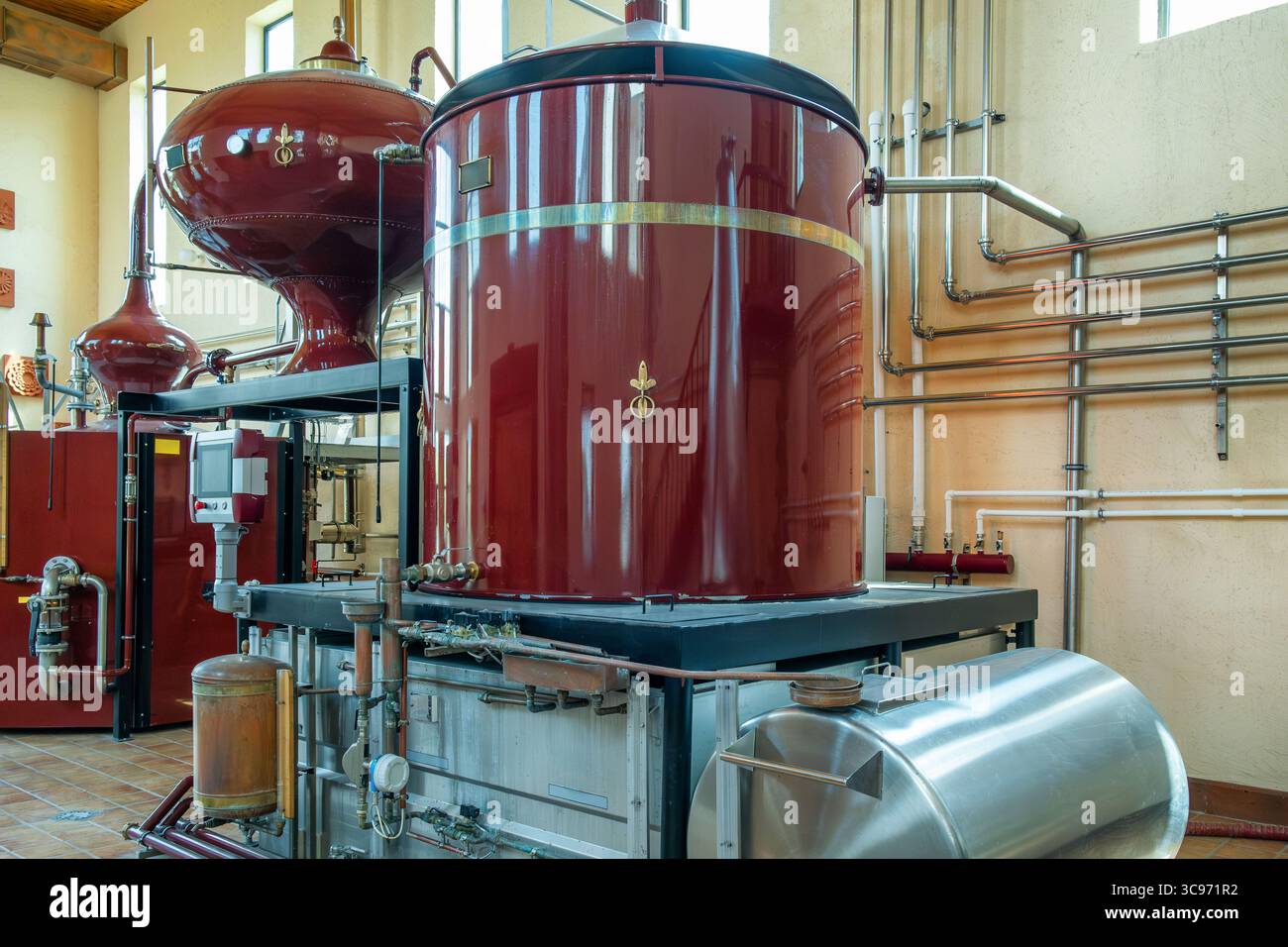 Brandy distillery with large red fermentation tanks with copper piping ...