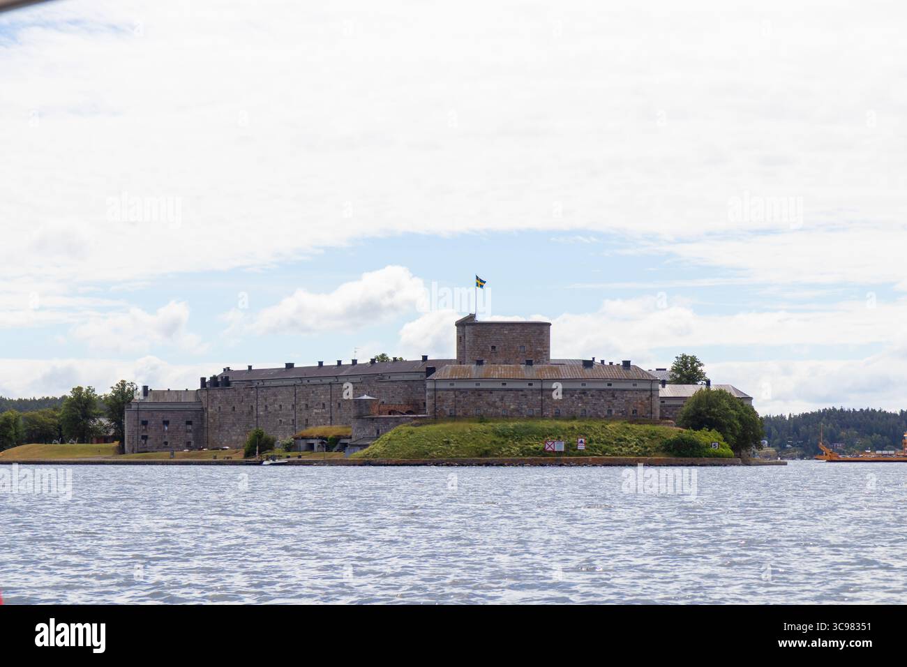 The historic stone Vaxholm Fortress stands surrounded by water and lush ...