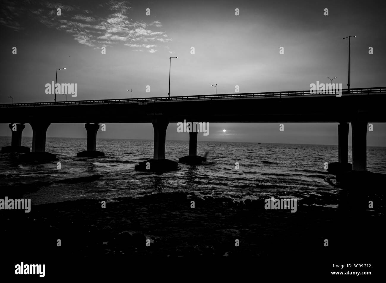 A modern bridge with tall concrete pillars stretches across the sea at ...