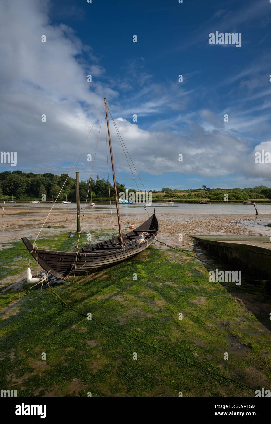 Old wooden boat with mast sitting on mud. View of the quay at low tide ...