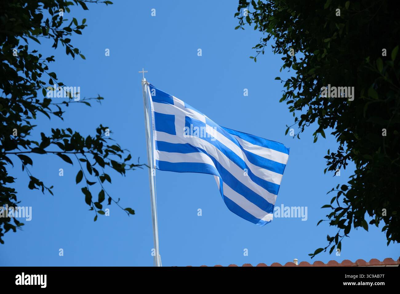The Greek flag flies between trees on the island of Rhodes Stock Photo ...