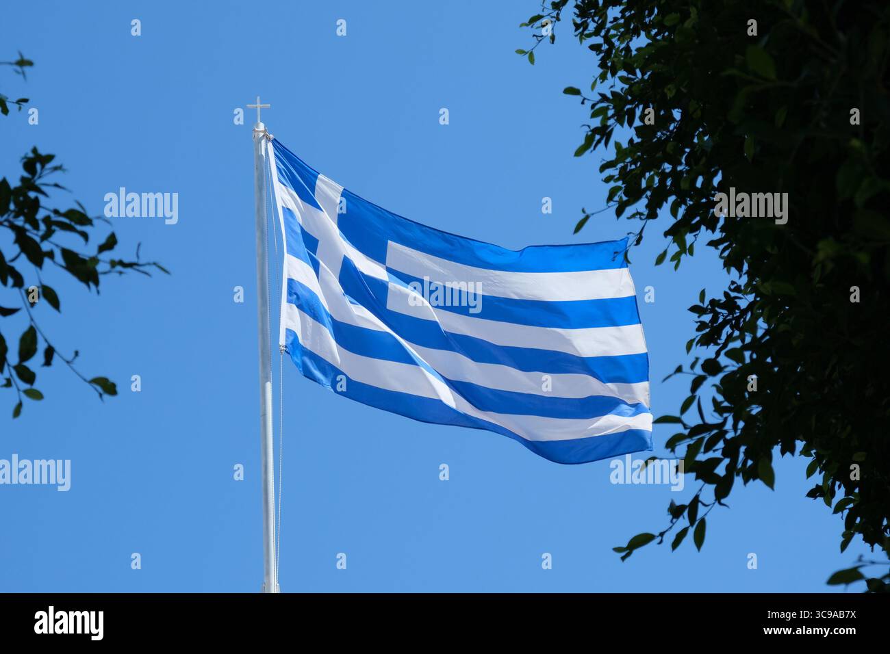 The Greek flag flies between trees on the island of Rhodes Stock Photo ...