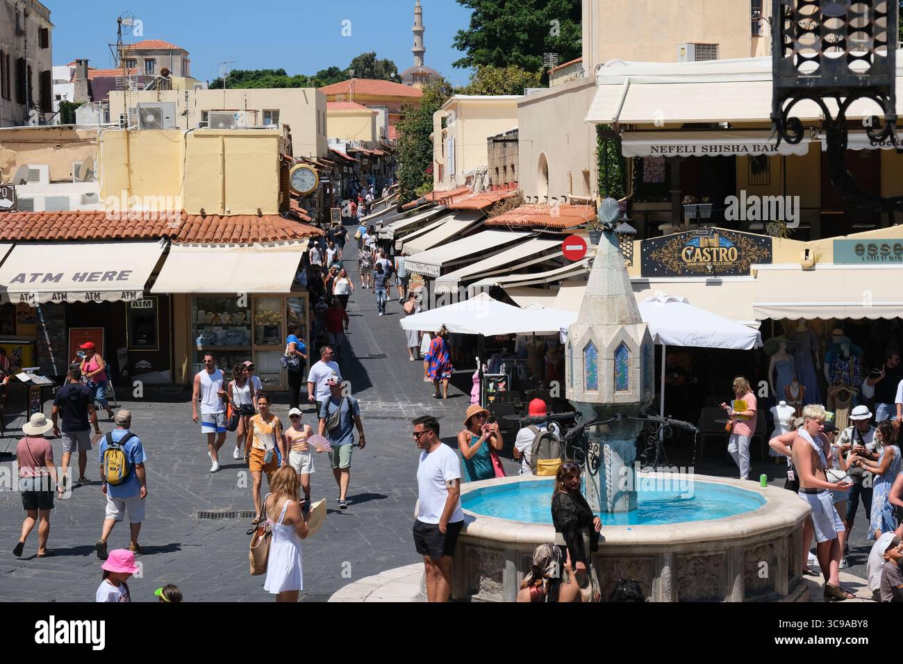 Tourists mill around a fountain in Hippocrates Square in the heart of ...