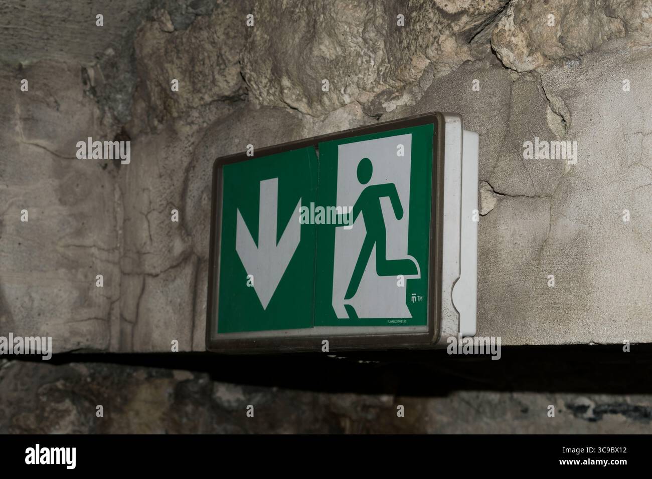 Safety exit sign with pictogram of person and arrow pointing down on ...