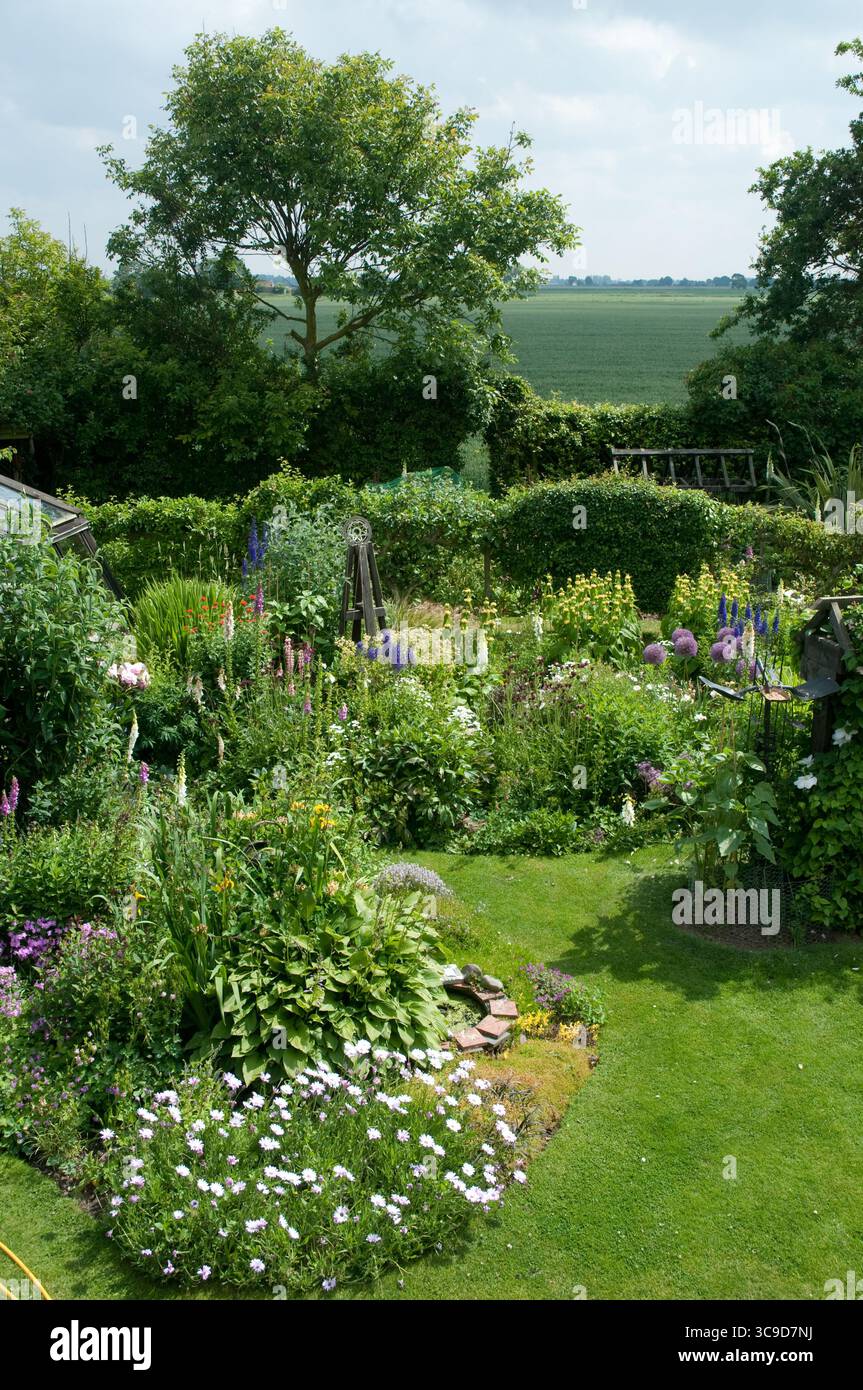 Lush flowers and greenery thrive in a cottage garden, surrounded by an ...