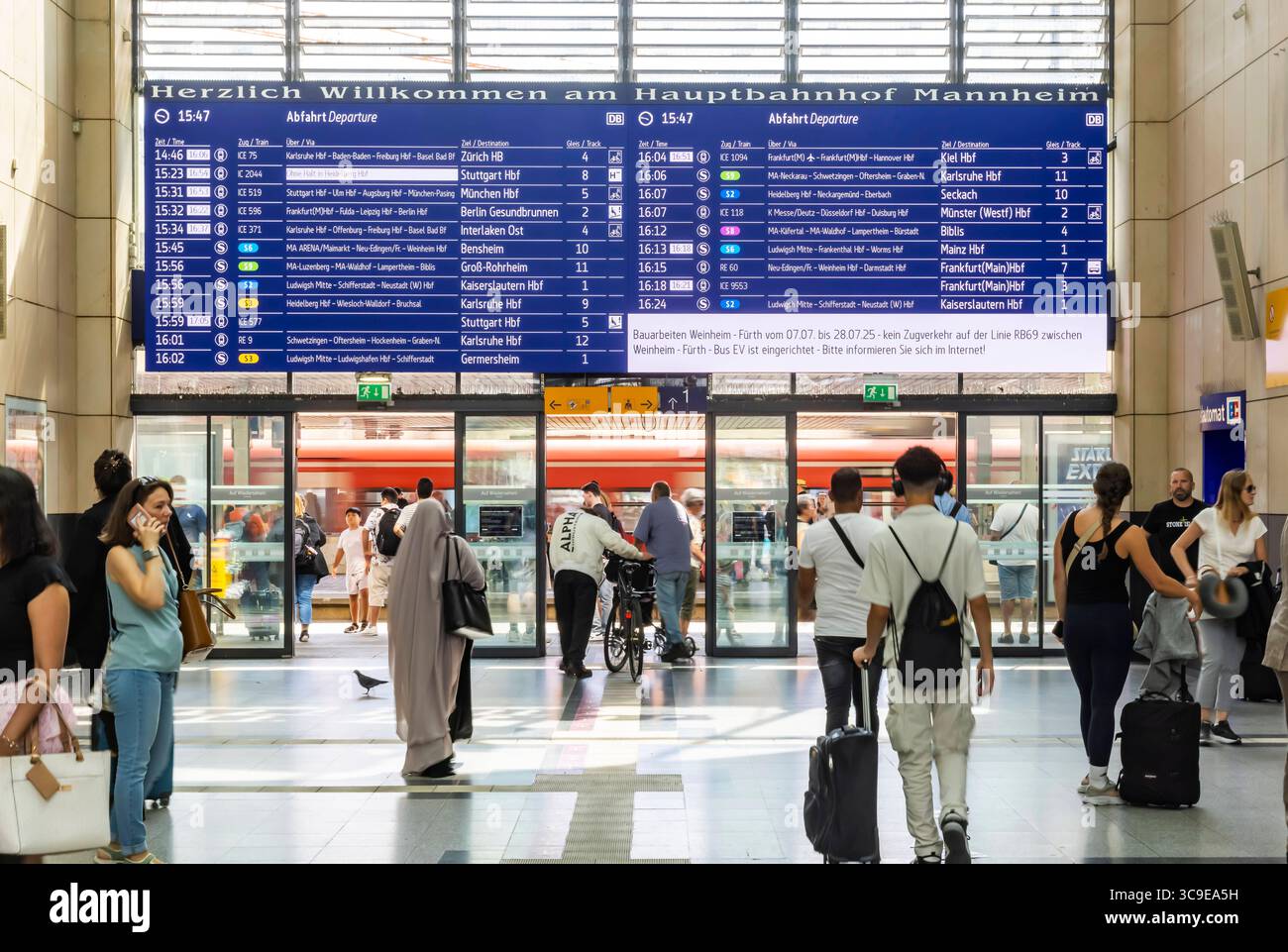 Hauptbahnhof Mannheim, Innenansicht mit Menschen und Anzeigentafel ...
