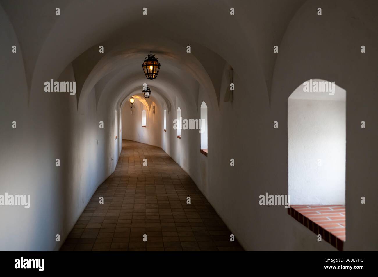 Long white arched monastery corridor with tiled floor and soft light ...