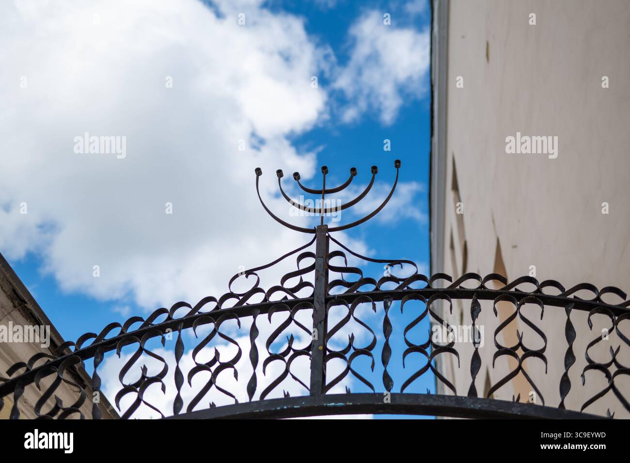 Artistic menorah design on a wrought iron fence with blue sky and white ...