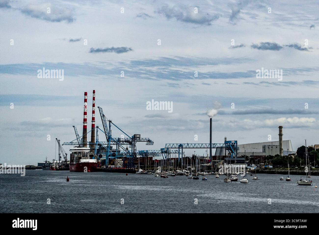 Dublin Port with Poolbeg chimneys, cargo cranes, container ship, and ...
