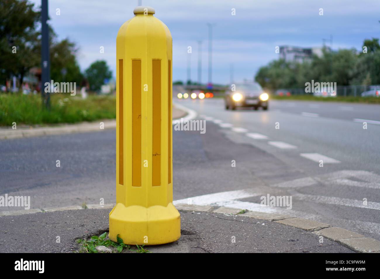 Yellow bollard in the center of a road used for lane separation and ...