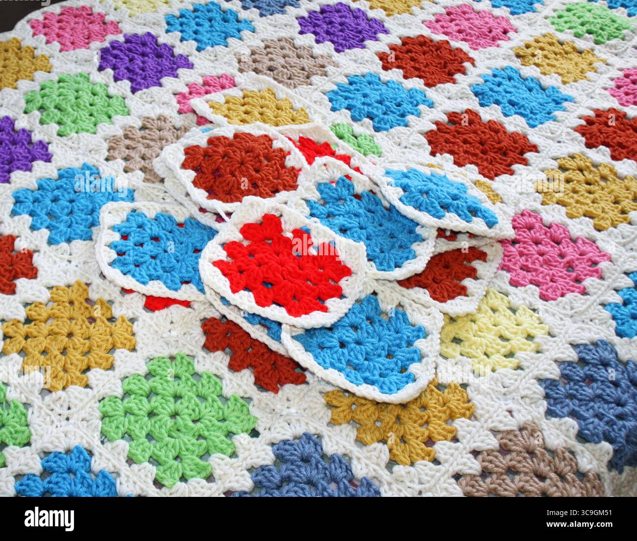 Colorful handmade crocheted granny squares laying on the surface of ...