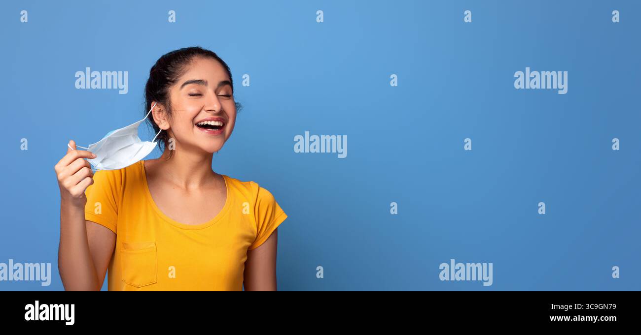 Smiling indian woman taking off disposable medical mask Stock Photo - Alamy
