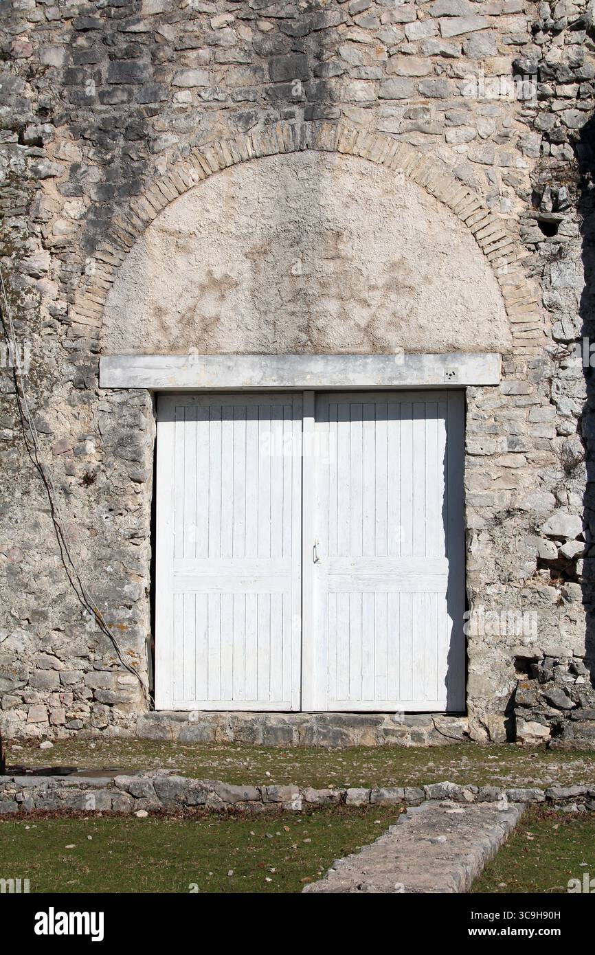 Historic stone wall features an arched lintel above closed double white ...