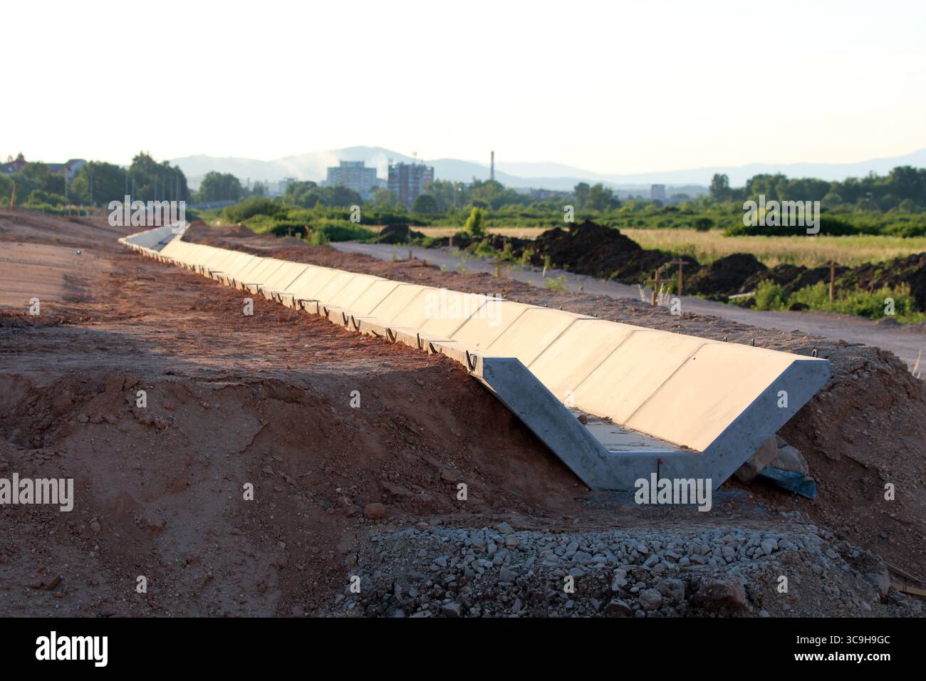 A newly built V-shaped concrete drainage channel stretches through a ...