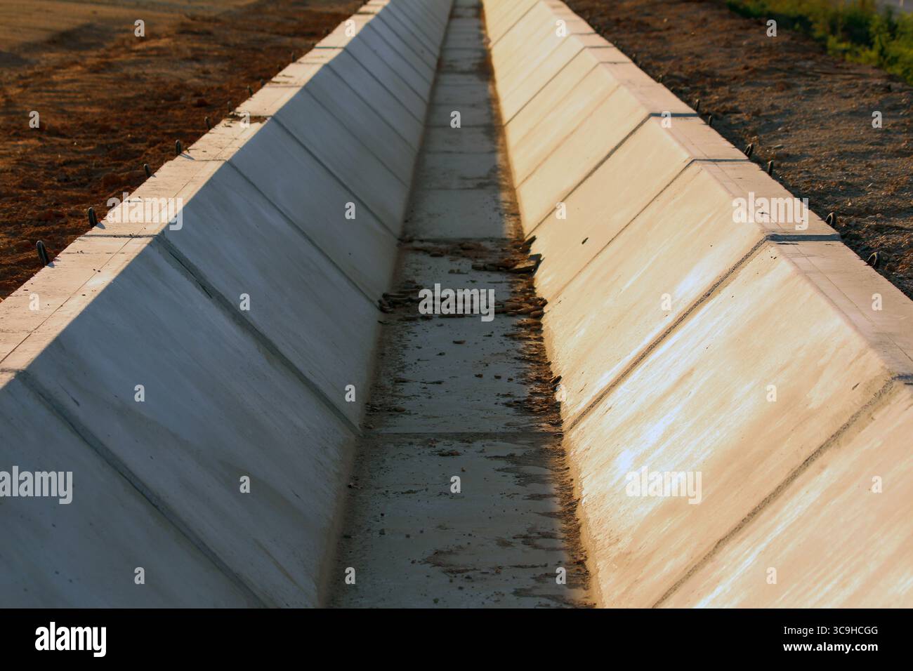 A long, symmetrical concrete drainage channel stretches into the ...