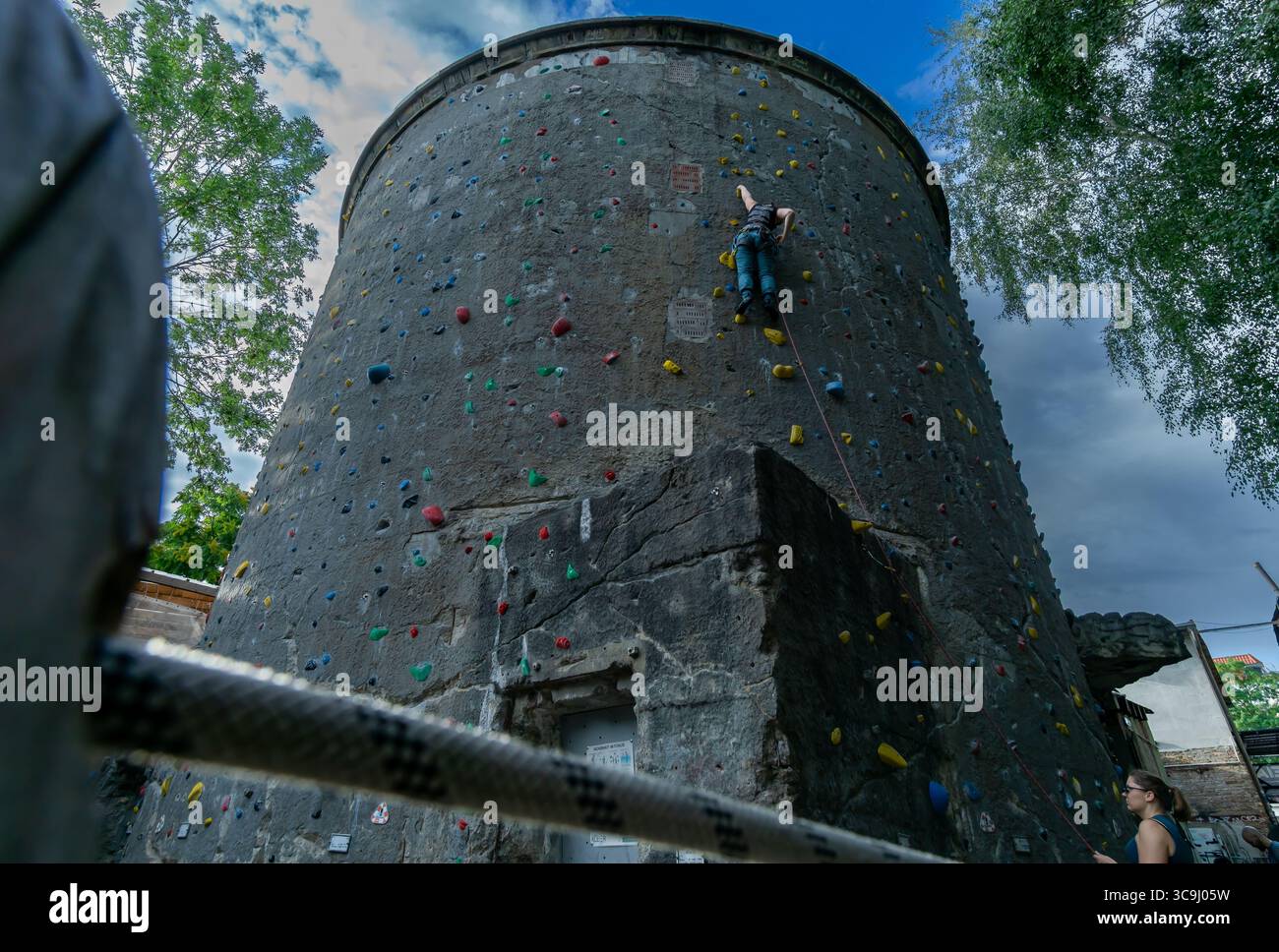 Climber ascending Der Kegel outdoor climbing tower in Berlin ...