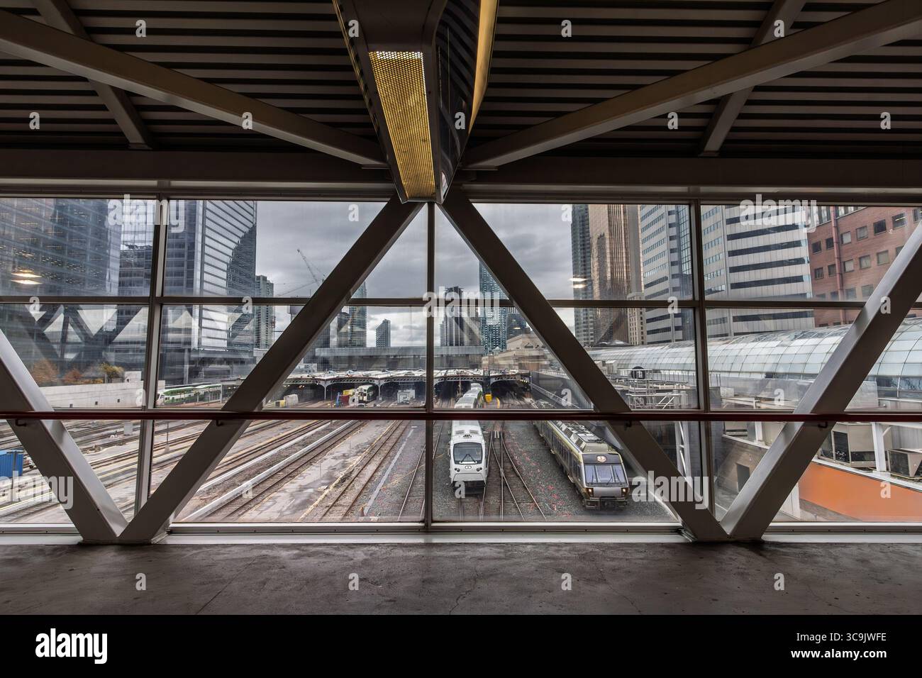 View through steel and glass skywalk toward tracks and Transit trains ...