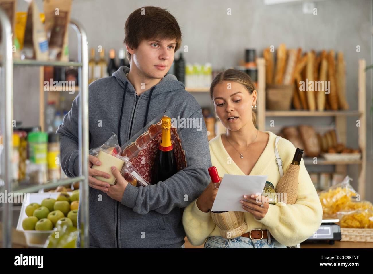 Young couple shopping together, choosing items from a pre-made list at ...