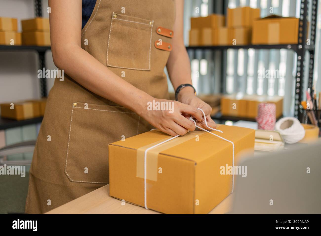 Young female entrepreneur preparing package for delivery at her home ...