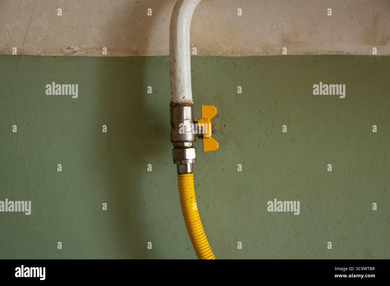 Old wall and gas pipe with yellow hose and valve in kitchen in ...