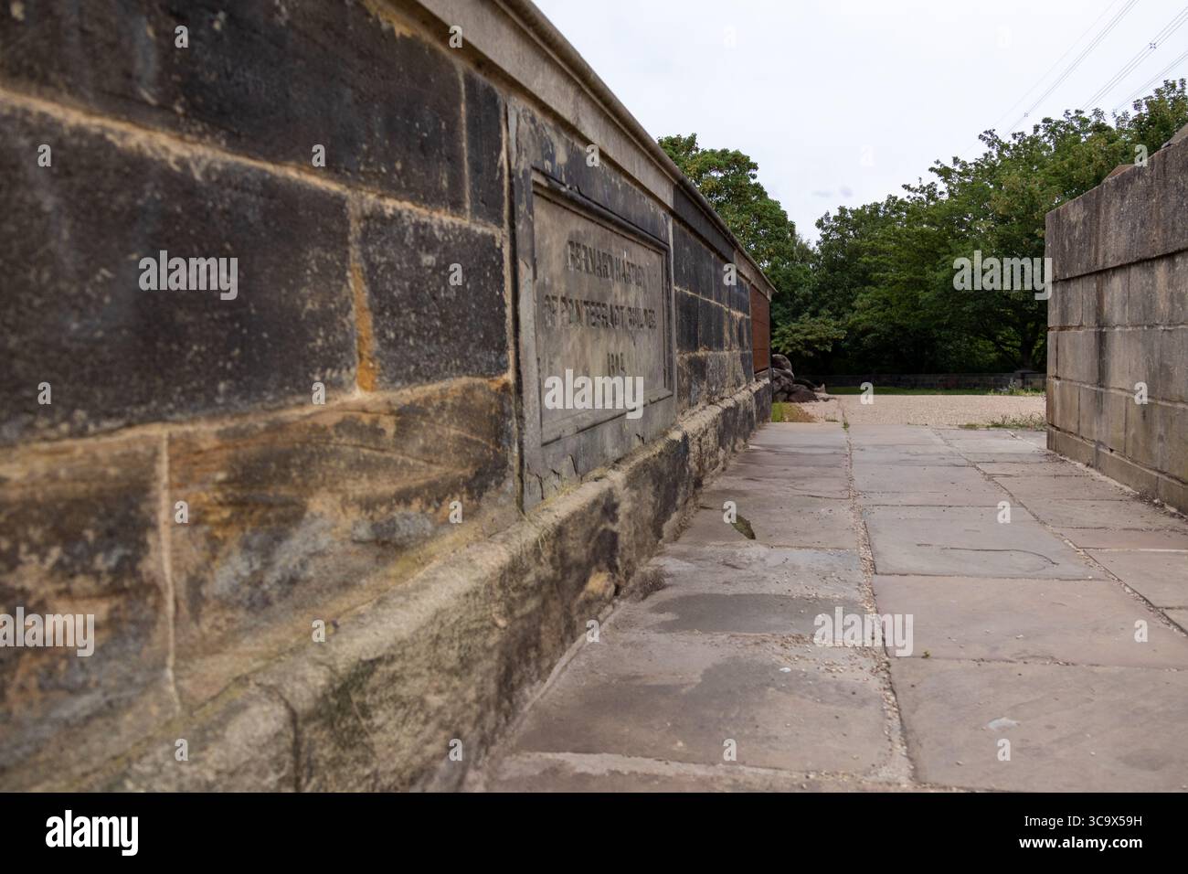 Close-up view of a stone bridge wall with engraved text and a paved ...