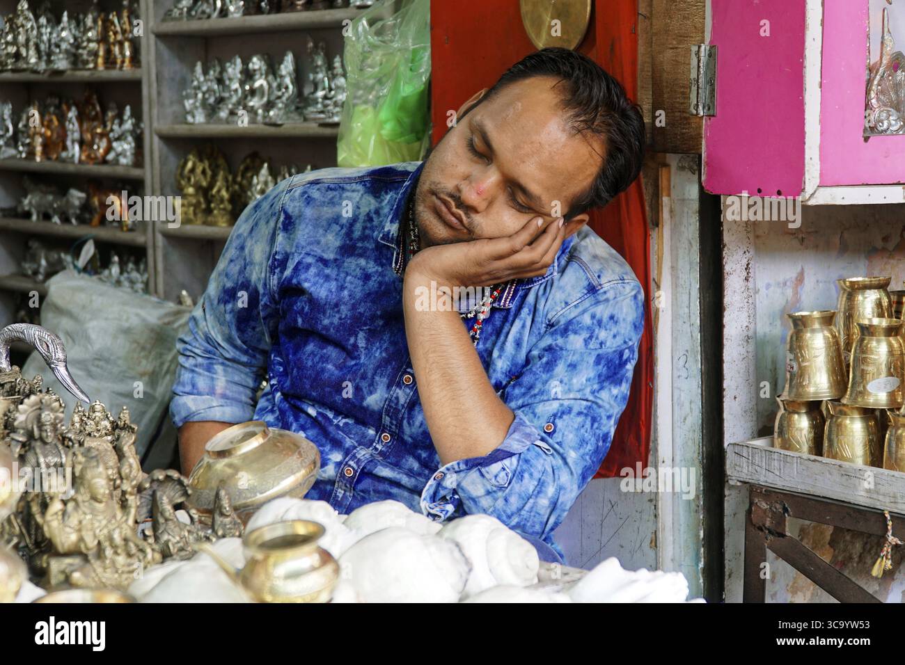 Man sleeping amidst metal objects in an Indian market stall, Pushkar ...