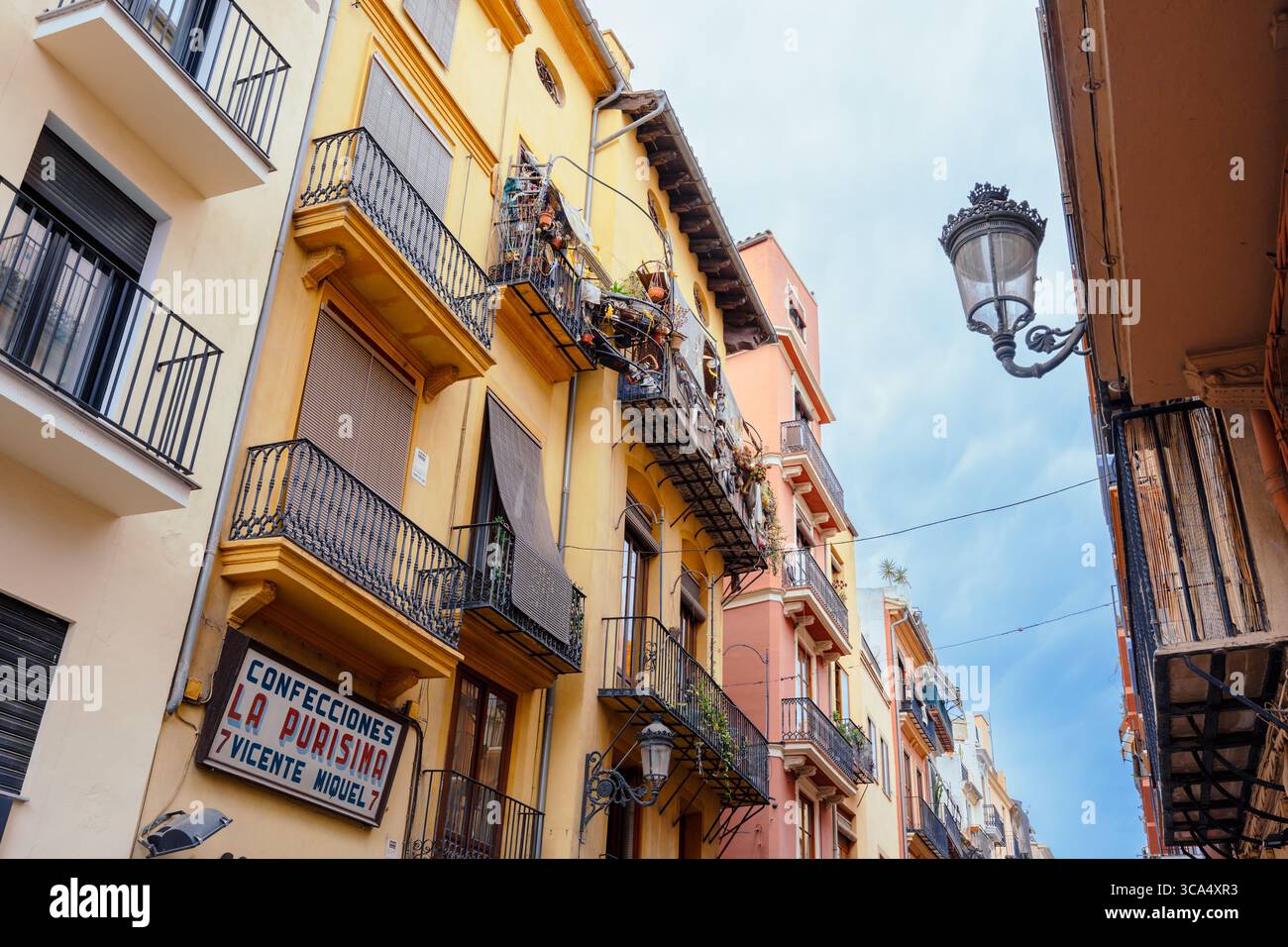 Valencia street with colorful buildings, hanging plants, cluttered ...