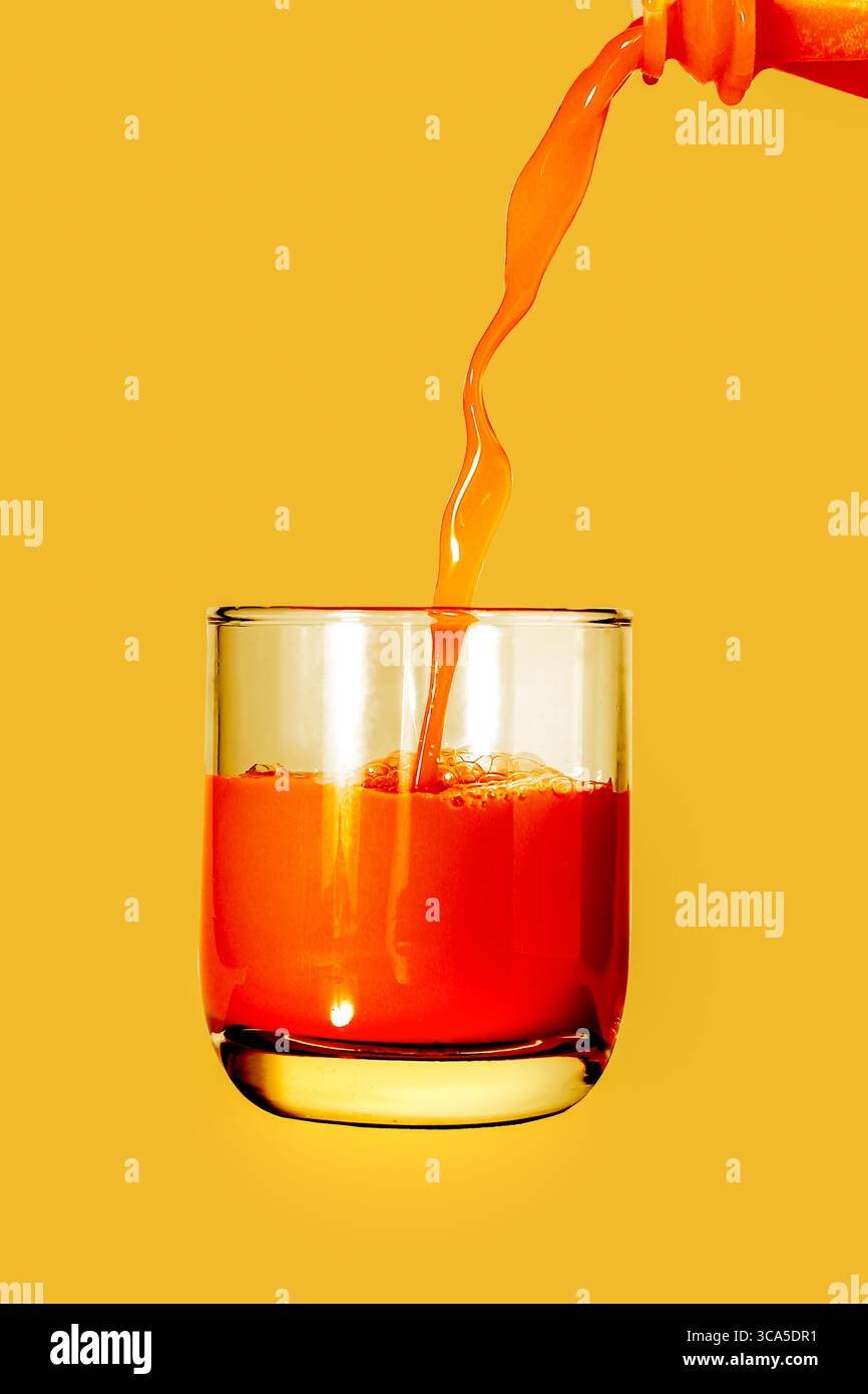Photograph of pouring orange juice into a cylindrical glass with a ...