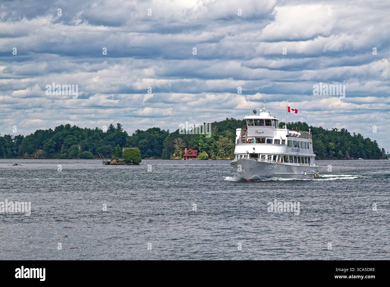 white tour boat, 3 decks, Canadian flag, moving through water, passing ...