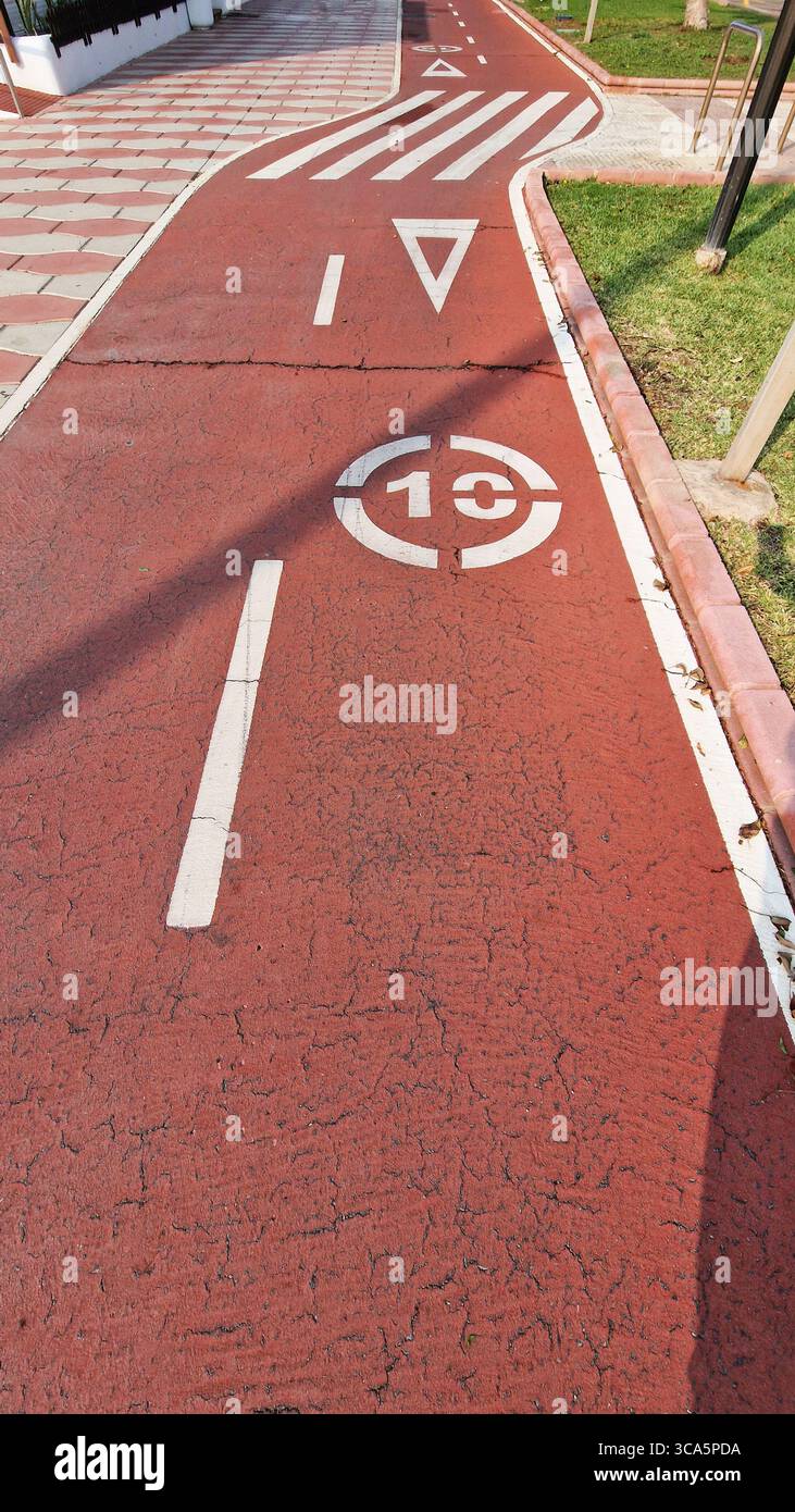 Urban bicycle lane features red pavement with white directional arrows ...