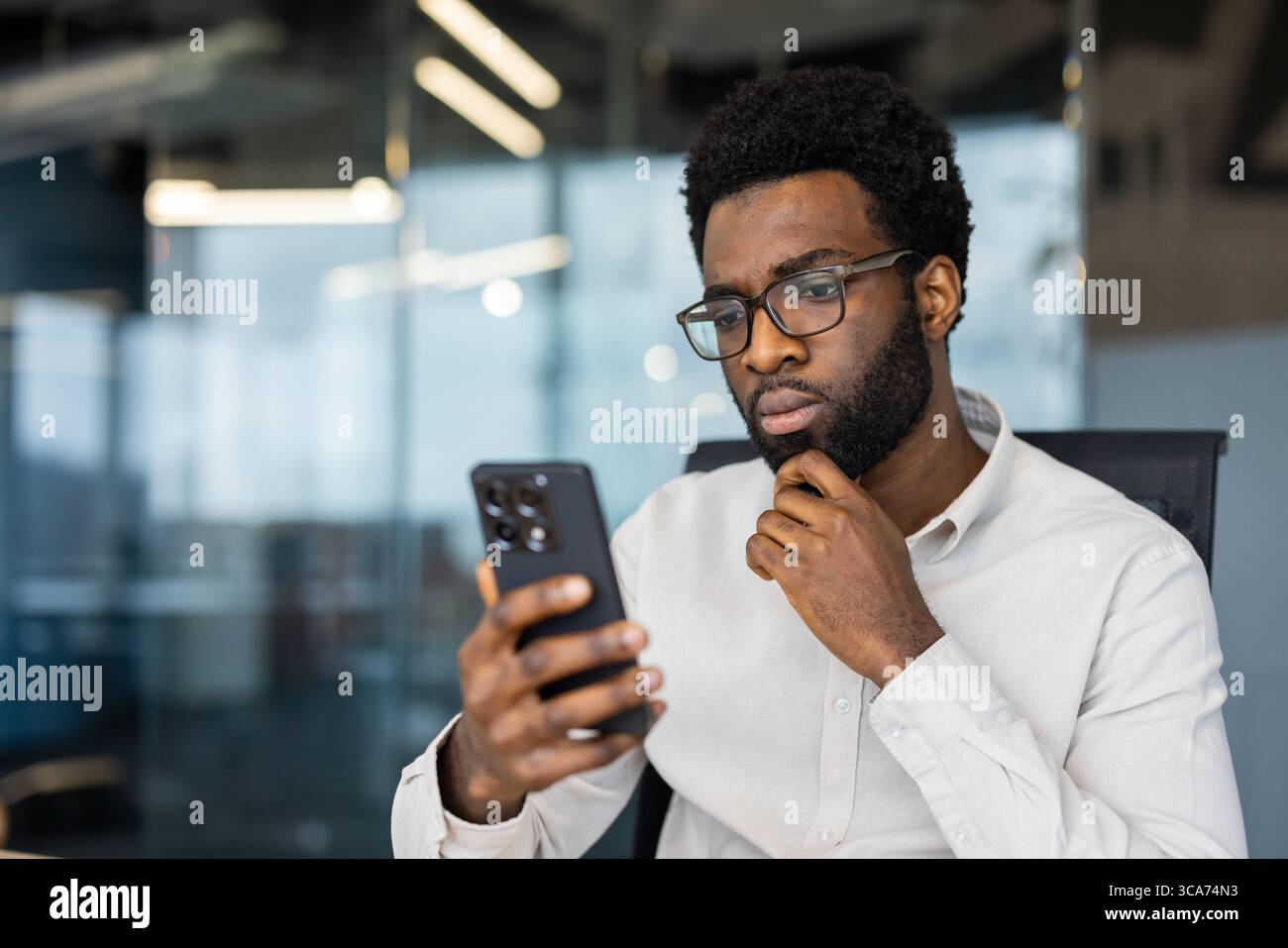 Person in an office setting attentively looking at his smartphone ...