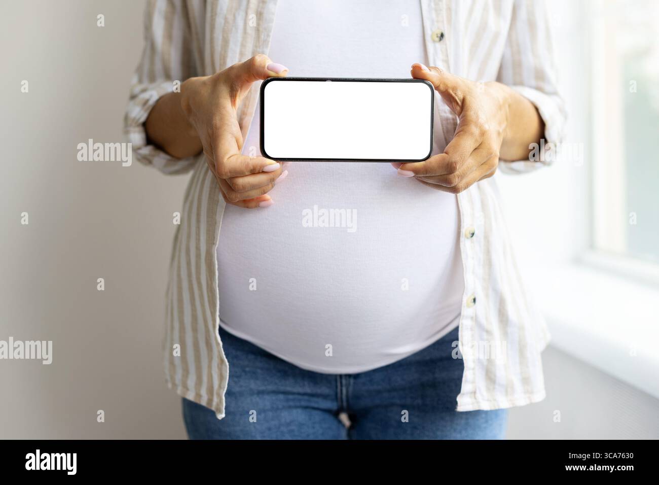 Pregnant woman holding horizontal smartphone with blank screen in front ...