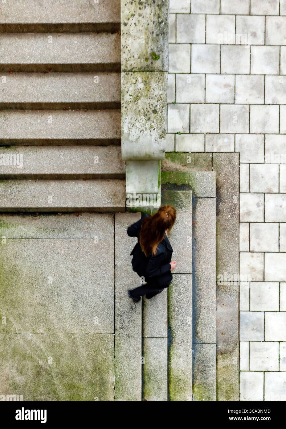 A woman with long red hair is walking down a set of stairs Stock Photo ...