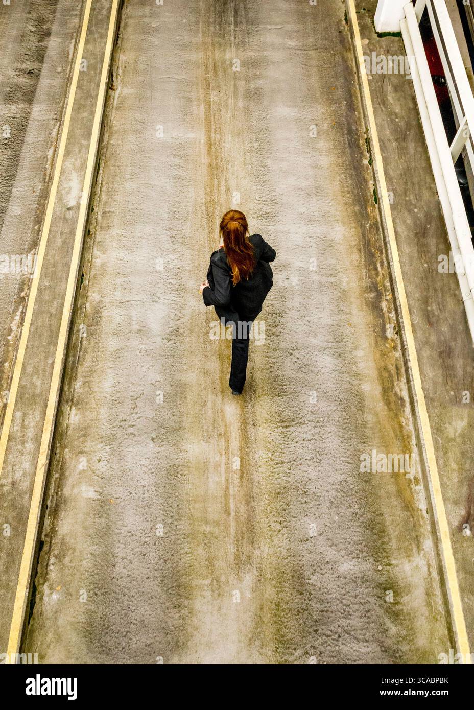 An overhead shot of a woman in a black suit running down a concrete ...
