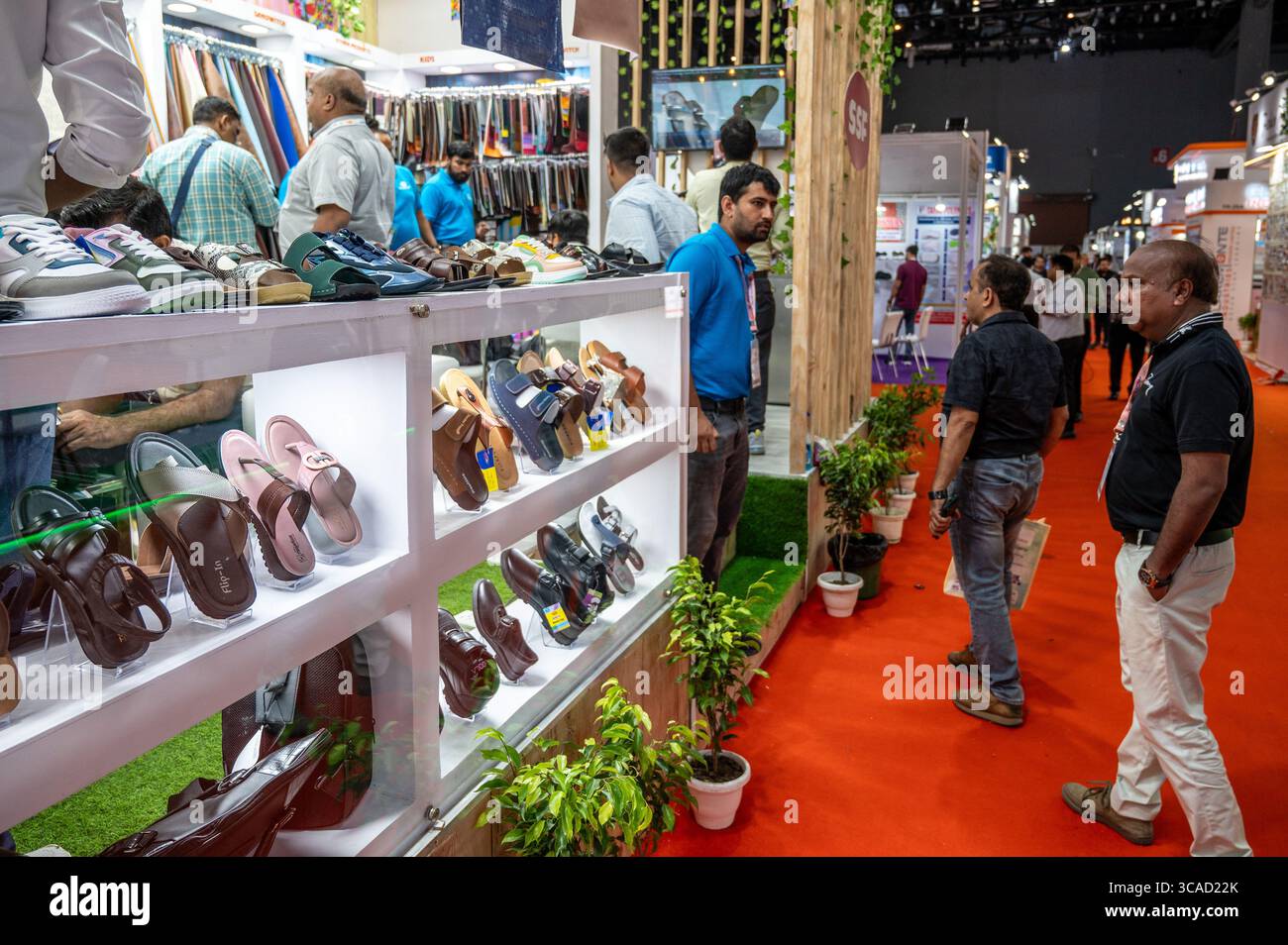 Visitors or shoe traders seen checking details of a shoe on display at ...