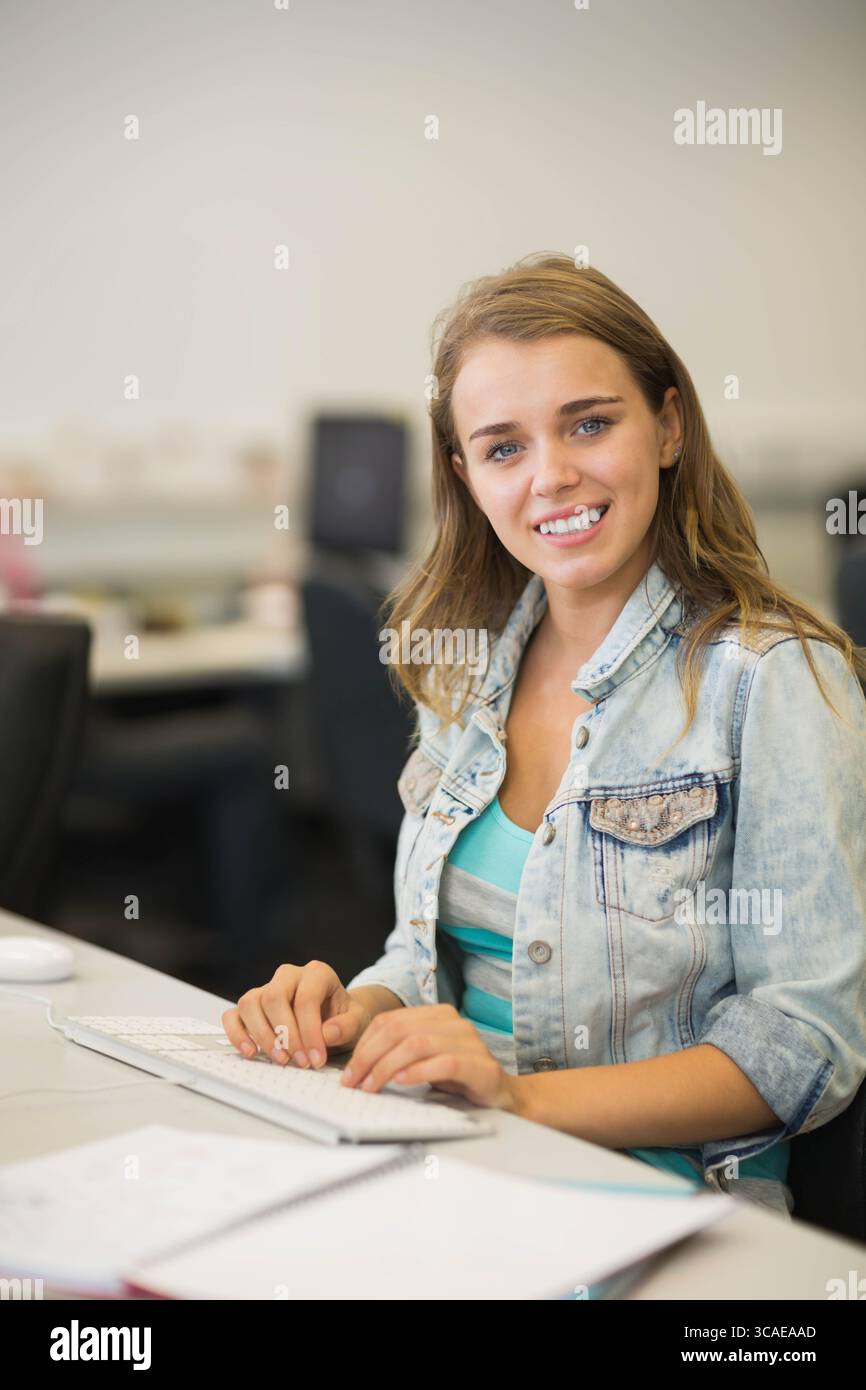 Female worker wearing denim jacket typing on keyboard at computer lab ...