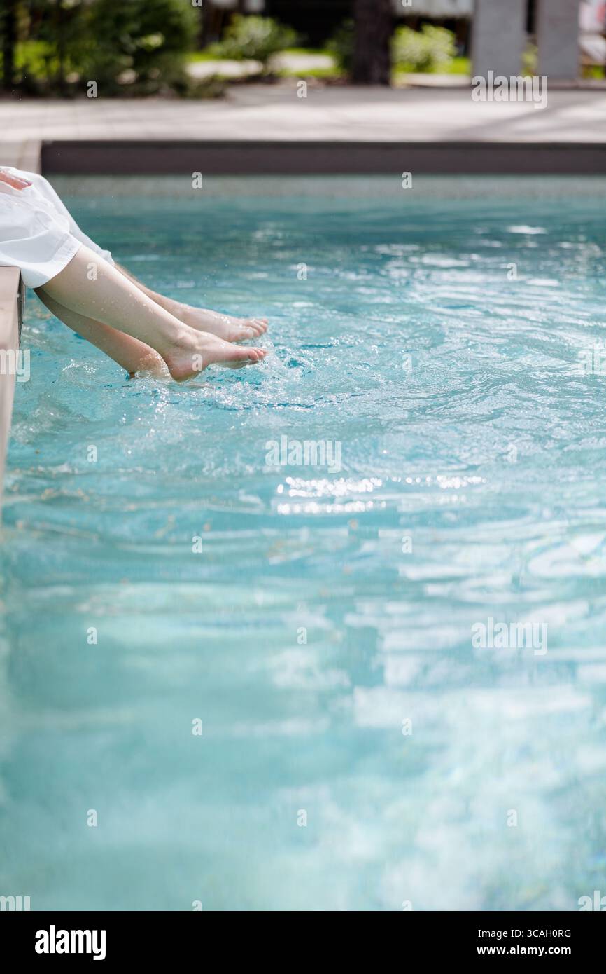 Couple Sitting Poolside with Feet in Water Stock Photo - Alamy