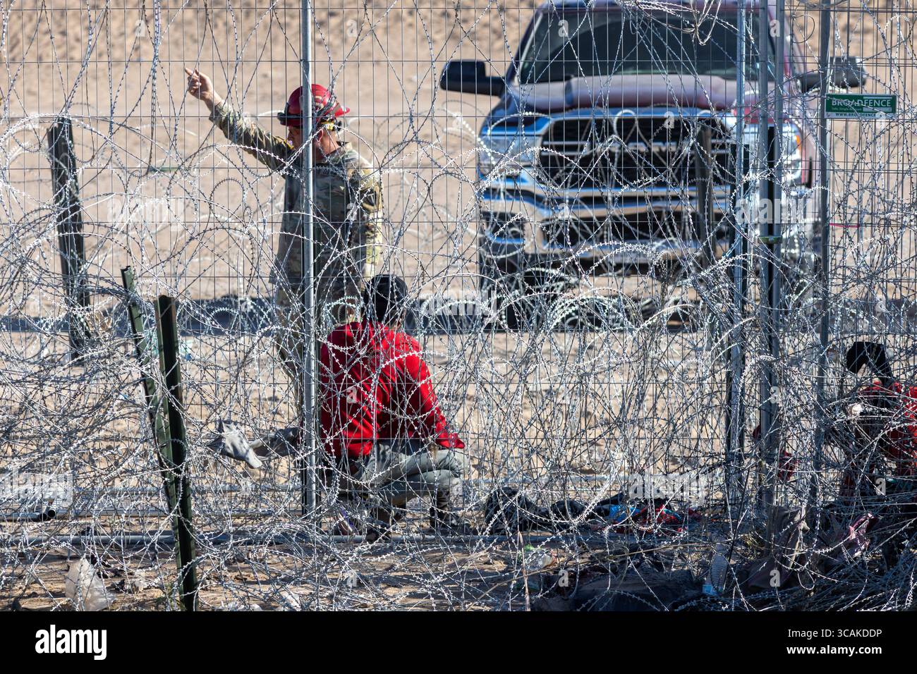 Civilians at Ciudad Juarez navigate concertina wire as a border agent ...
