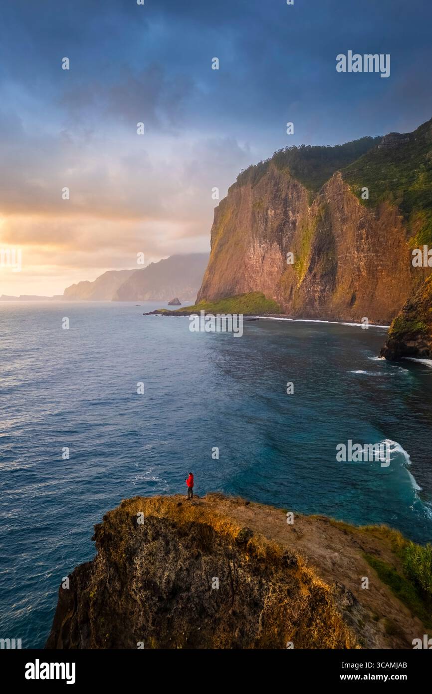 Aerial view of a tourist admiring sunrise from the cliffs of Miradouro ...
