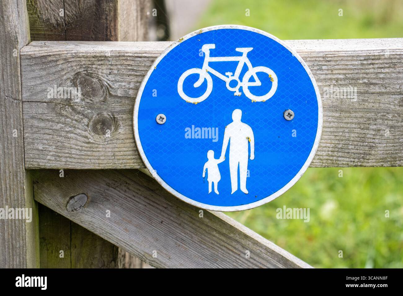 blue and white multi use cycle and footpath sign on a grey wood fence ...