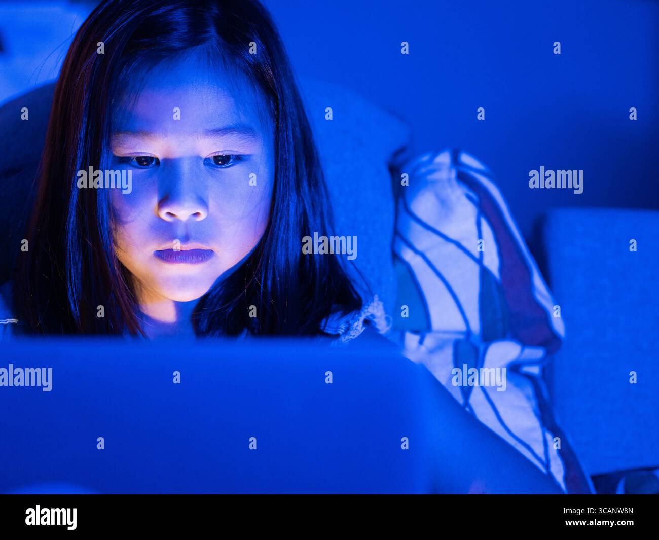 Asian girl sitting on the couch watching laptop at night. Parental ...