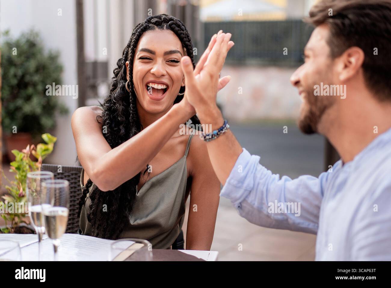 A happy young diverse couple laughs and gives a high five in ...