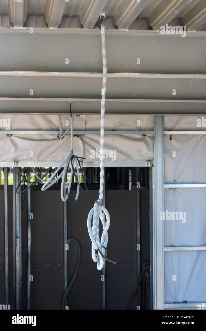 Exposed flexible electrical conduits hang from a metal ceiling in a ...