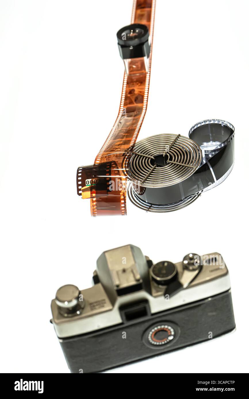 Vintage camera and long film strip coiled through a reel on a white ...