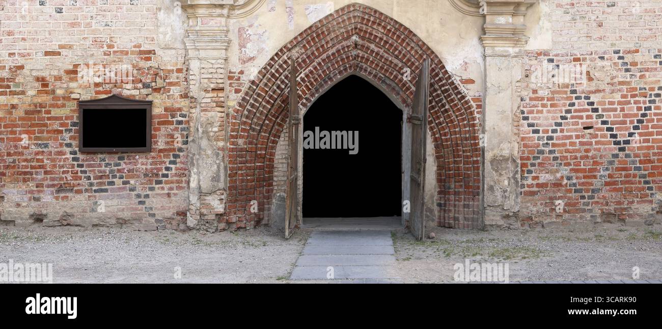 Open arch doors to the old ruined village aged church of red bricks ...